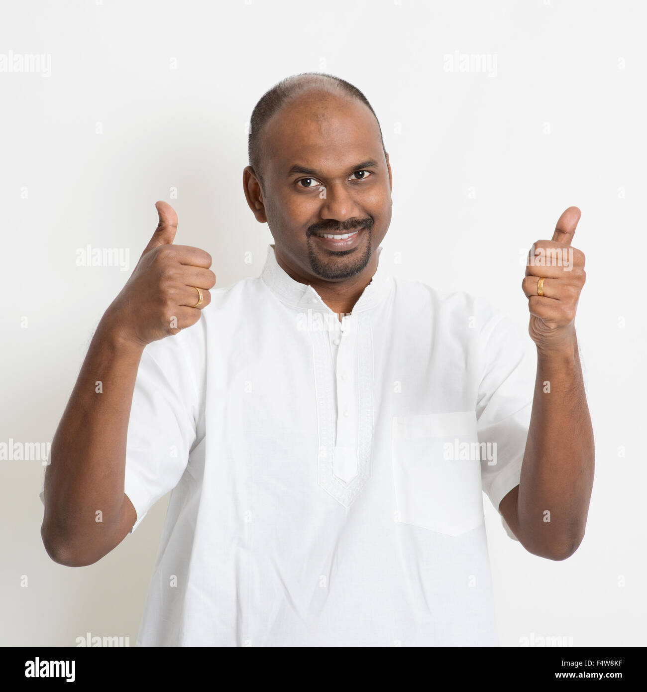 Portrait of happy mature casual business Indian man thumbs up, standing ...