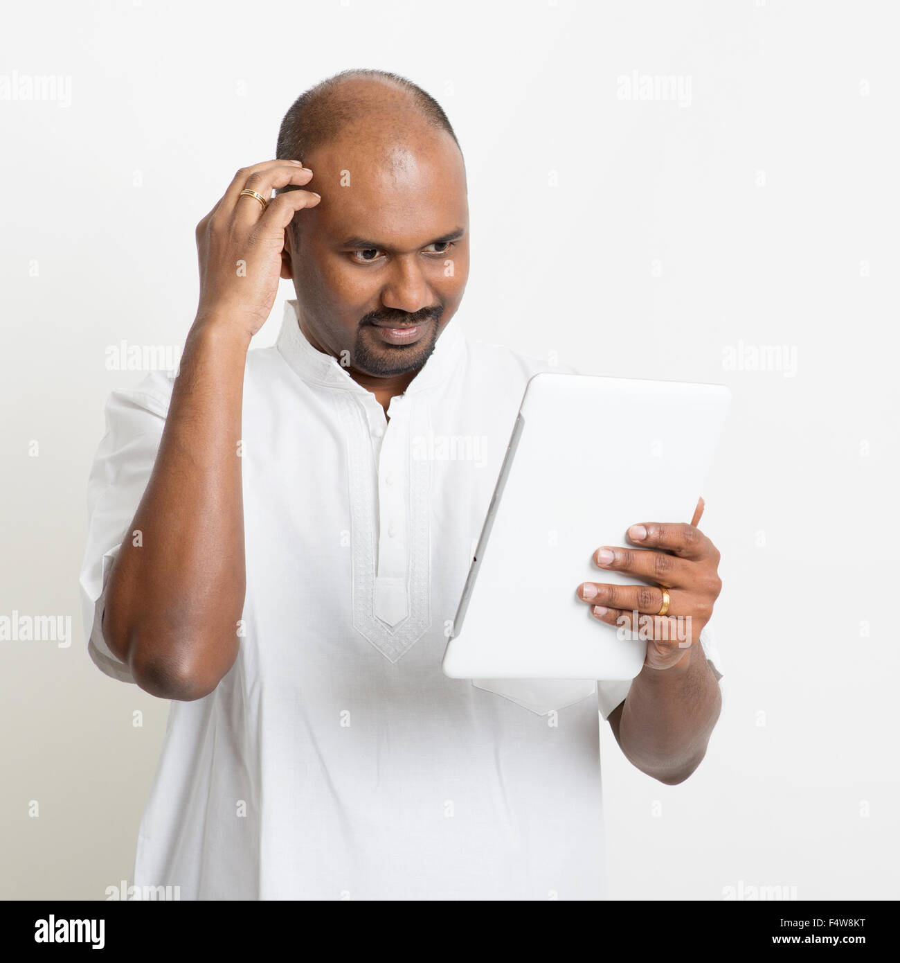 Portrait of mature Indian man headache while reading on digital tablet ...