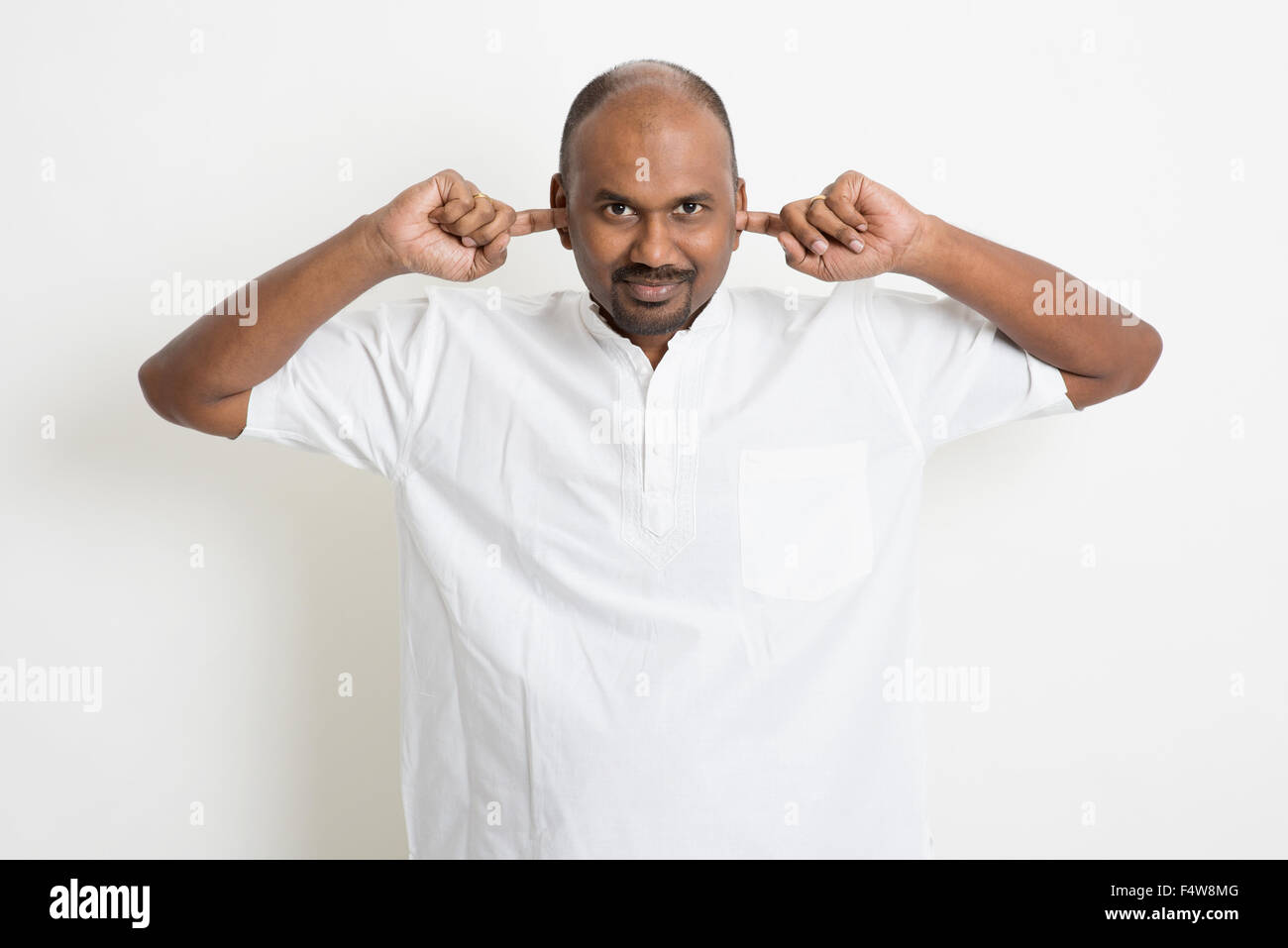 Portrait of mature casual business Indian man covered ears, standing on ...