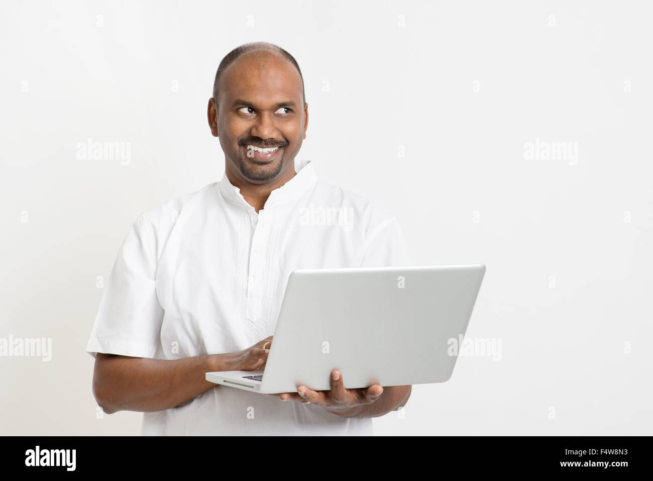 Portrait of mature casual business Indian man using laptop computer ...