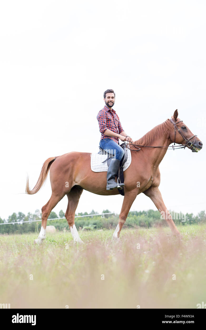 Portrait smiling man horseback riding in rural field Stock Photo - Alamy