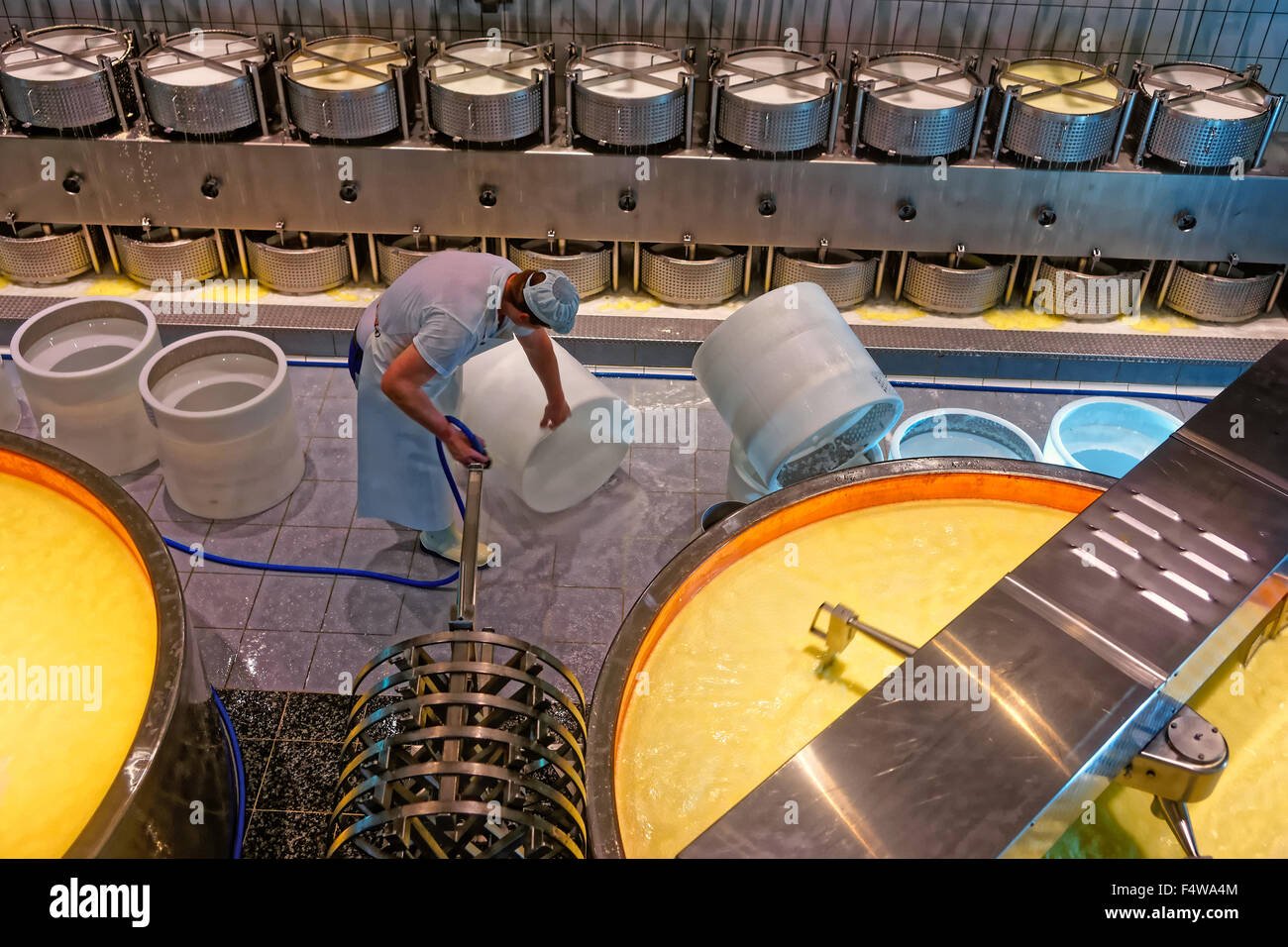 GRUYERE, SWITZERLAND - DECEMBER 31, 2014: Worker of the cheese-making ...