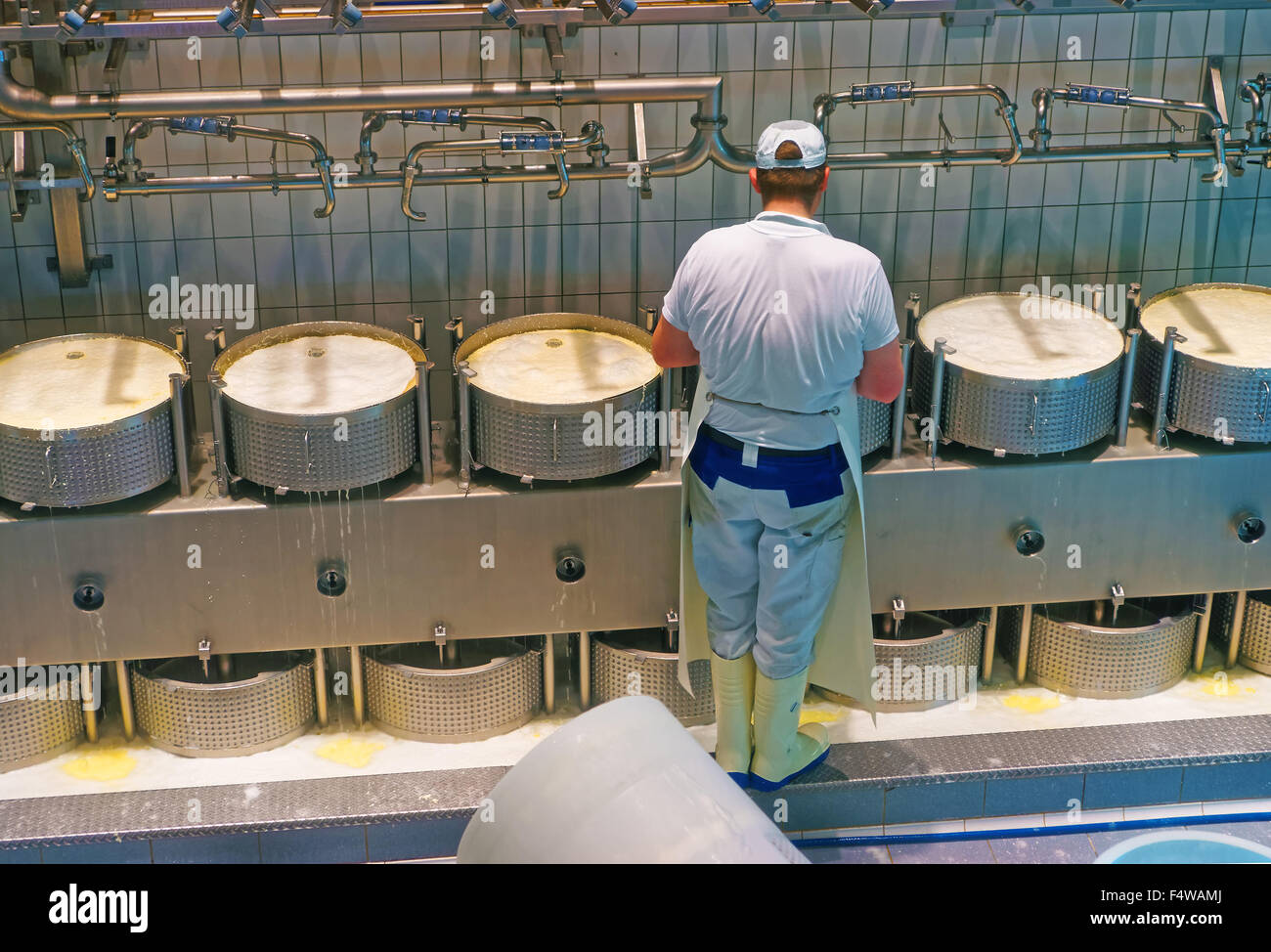 GRUYERE, SWITZERLAND - DECEMBER 31, 2014: Worker of the cheese making ...