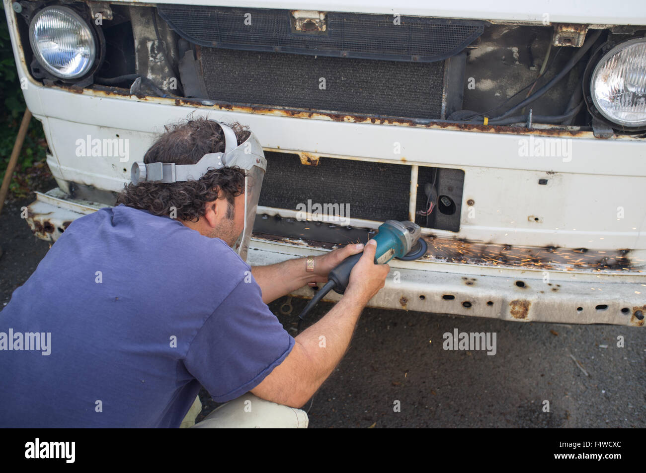 A man repairs damage to his camper van cutting out a section of ...