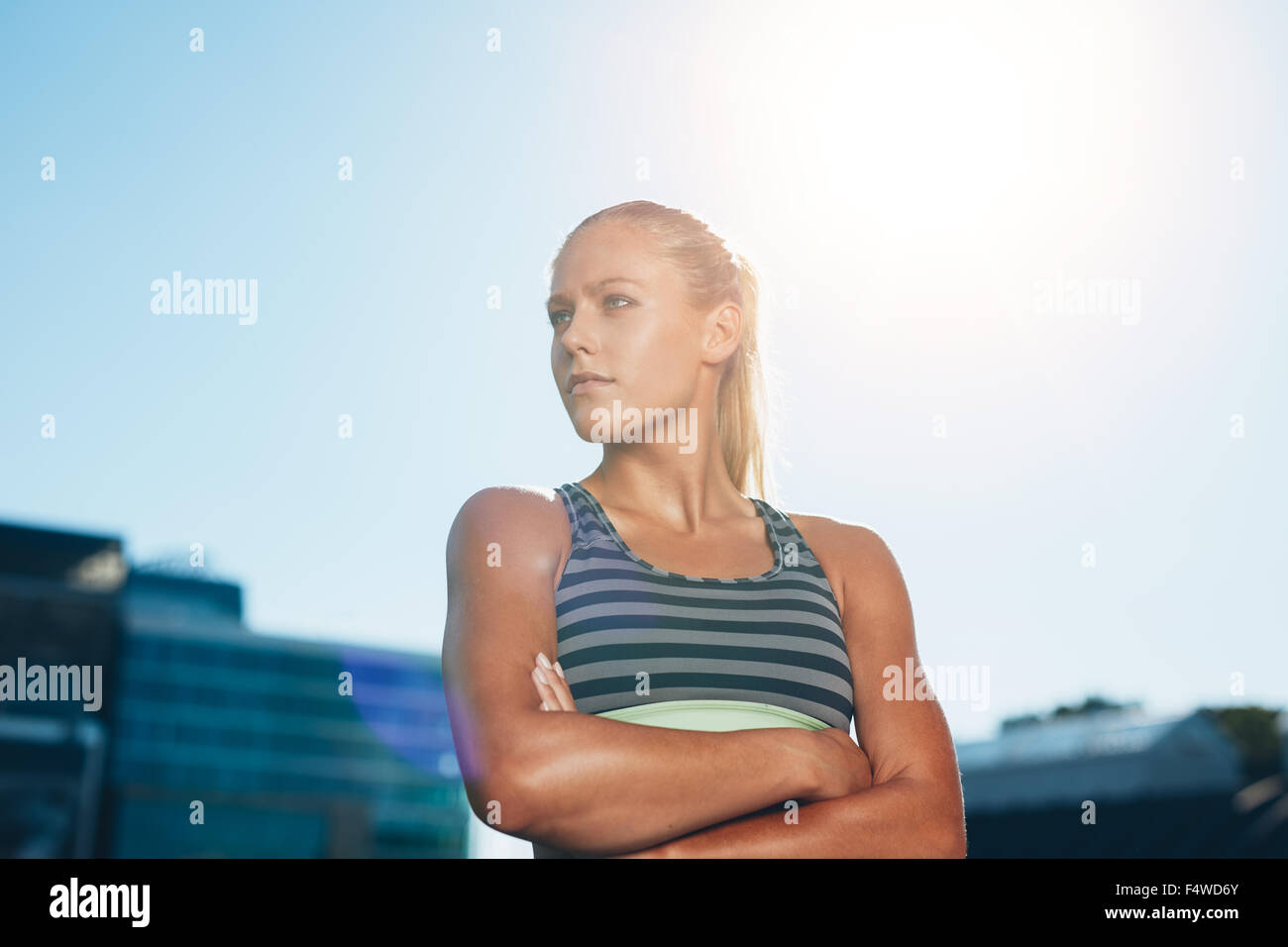 Portrait of a confident young runner standing looking away with her ...