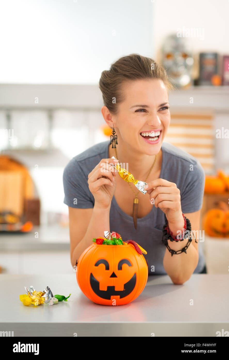 Halloween candy is so good! Happy young woman in decorated kitchen ...