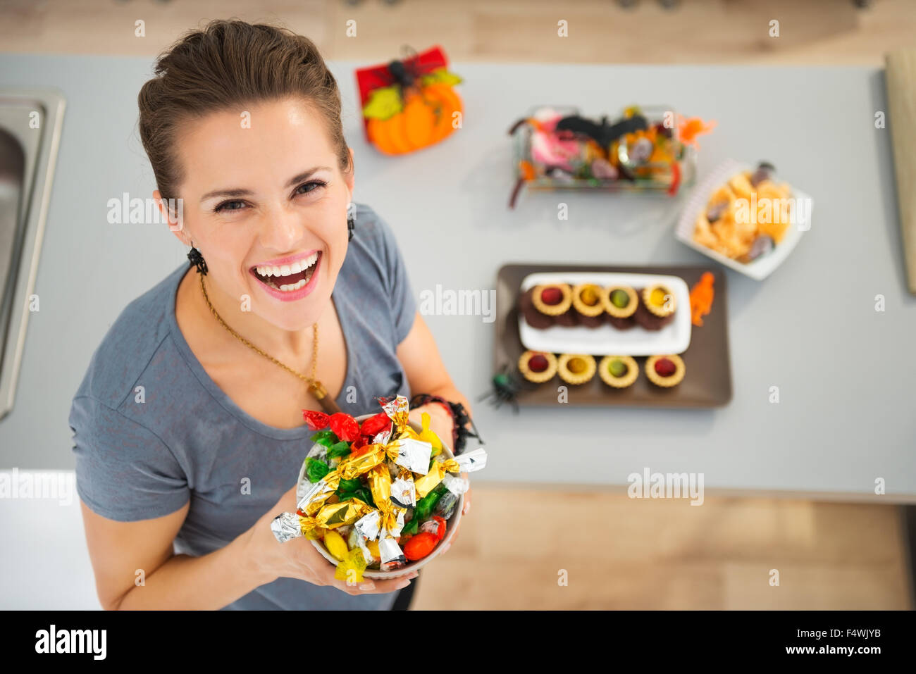 Halloween candy is never too much! Smiling young woman in kitchen ...