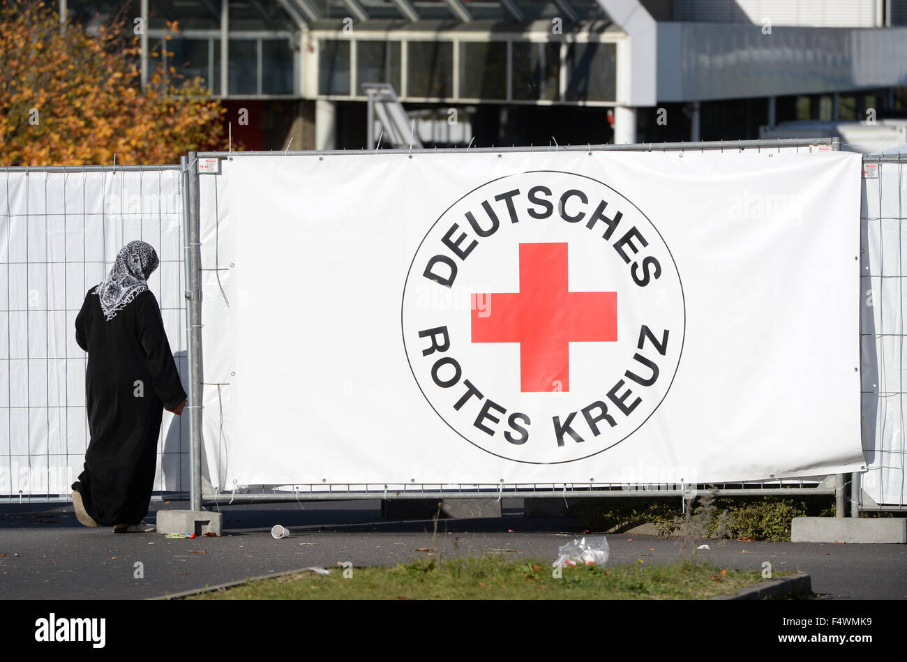 A woman stands before a German Red Cross logo at accommodation set-up ...
