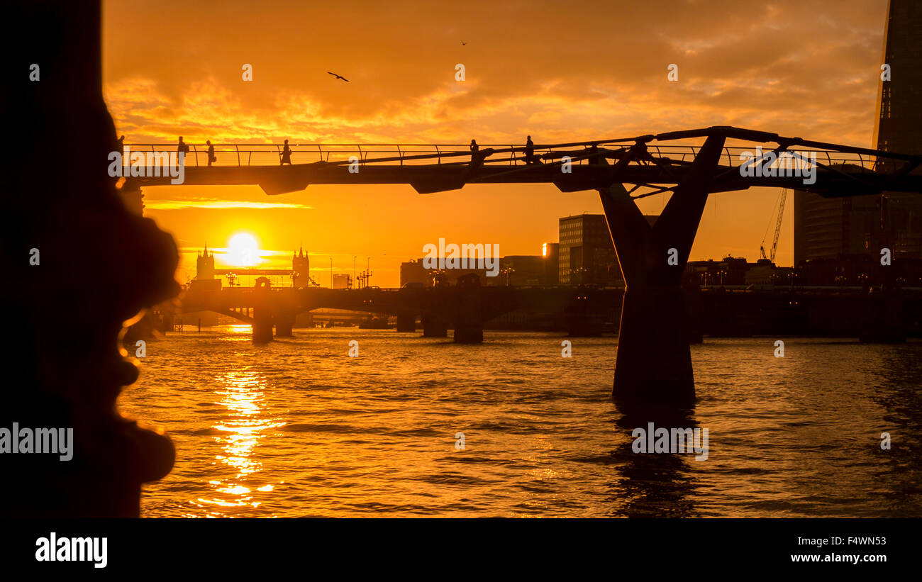 Early Morning sunrise over Millennium Bridge and Tower Bridge as people ...