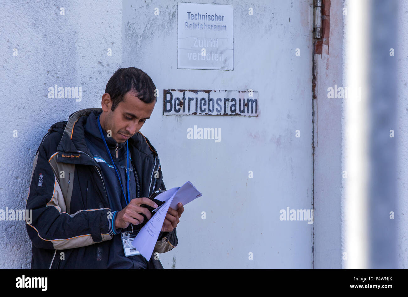 A refugee is standing with his documents waiting to be processed in the ...