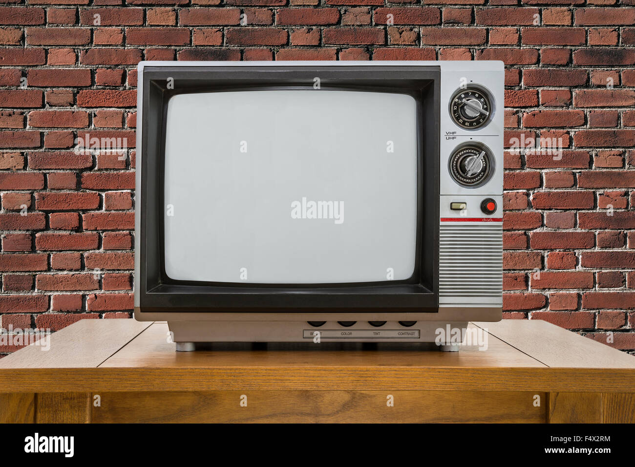 Vintage portable television and old wood table with red brick wall ...