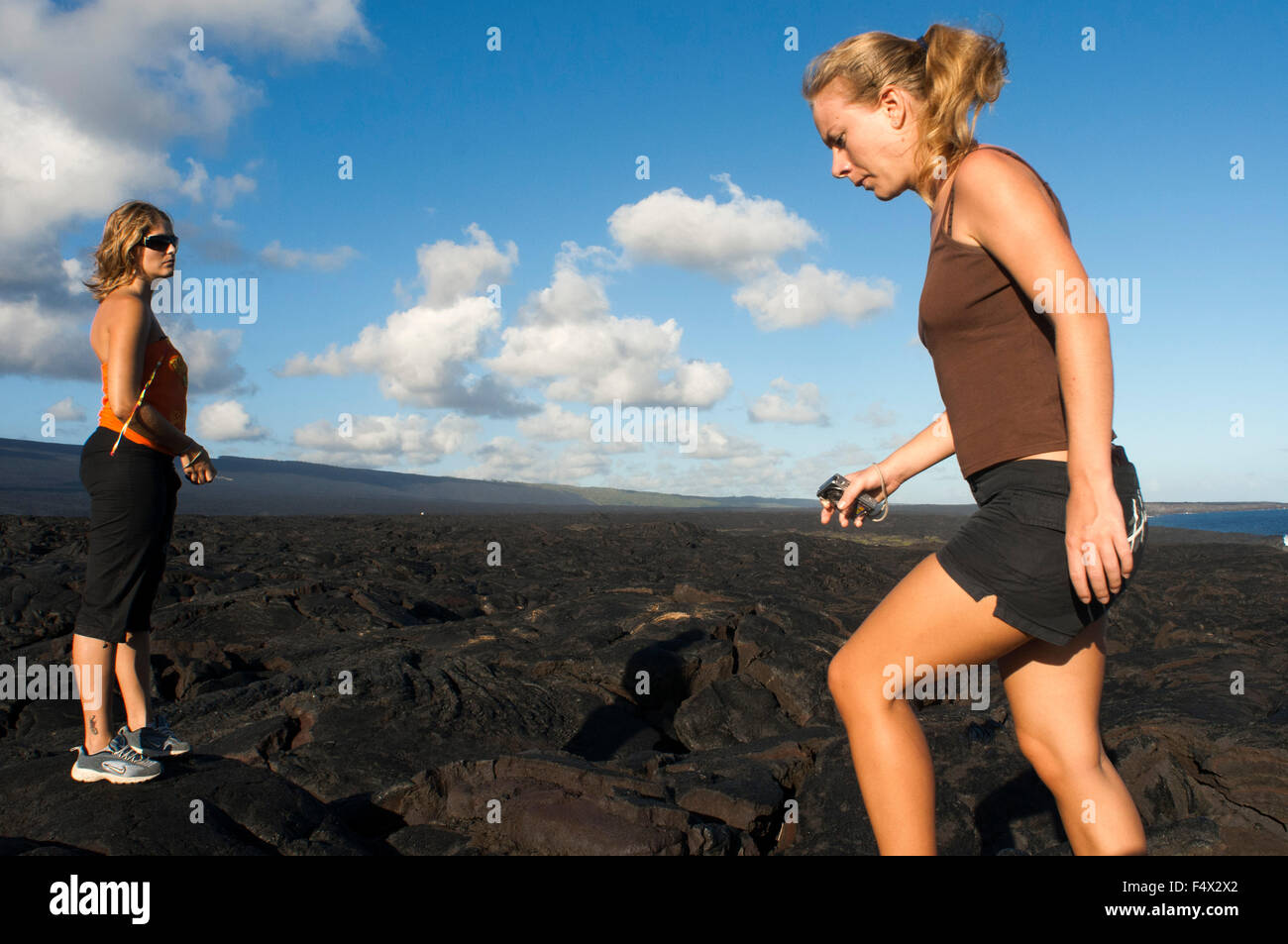 Tourists walking over the Black lava mountains near the coast and ...