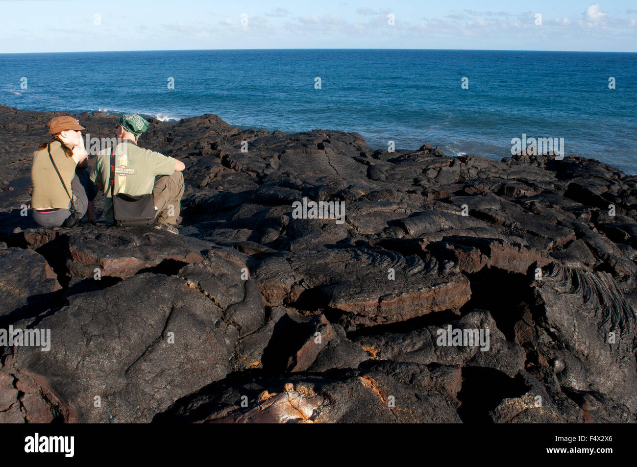 Friends sitting over the Black lava mountains near the coast and ...