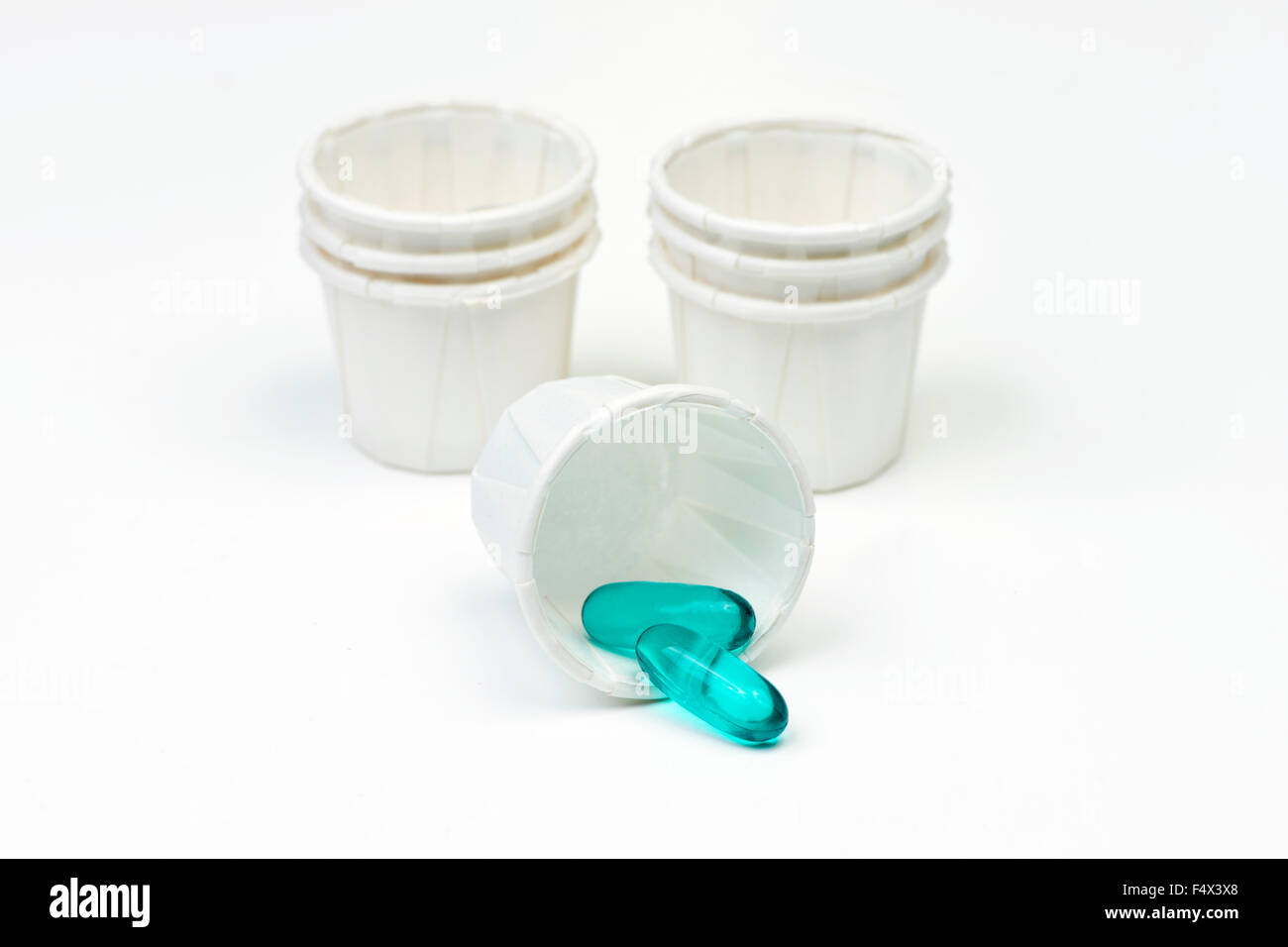 Blue gelatin capsules in white paper medicine dosage cup Stock Photo ...