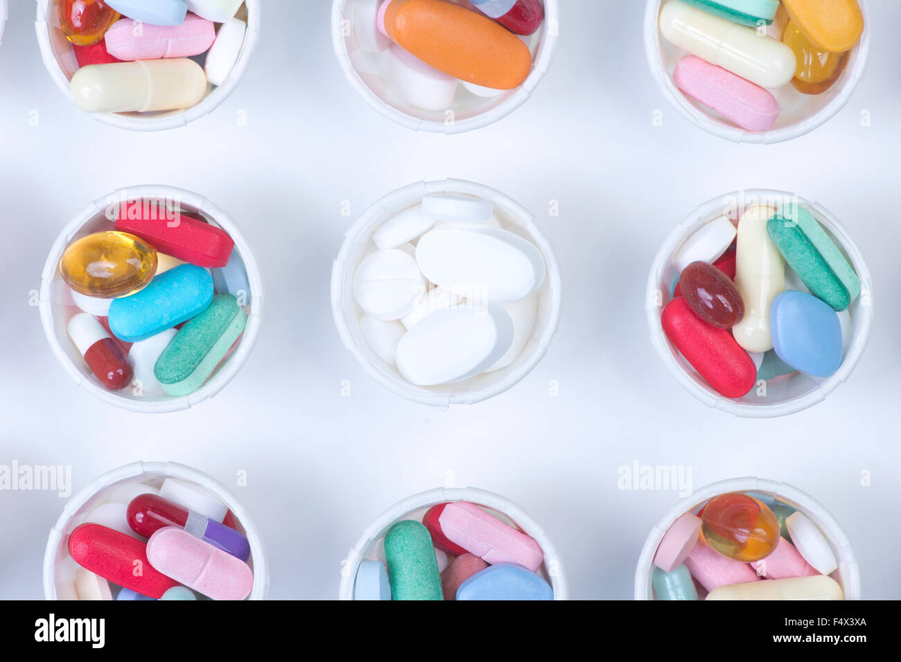 Many different assorted colorful pills in paper medication dosage cups ...