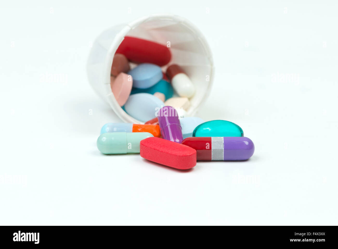 Different colorful medications spill from paper medication cup Stock ...
