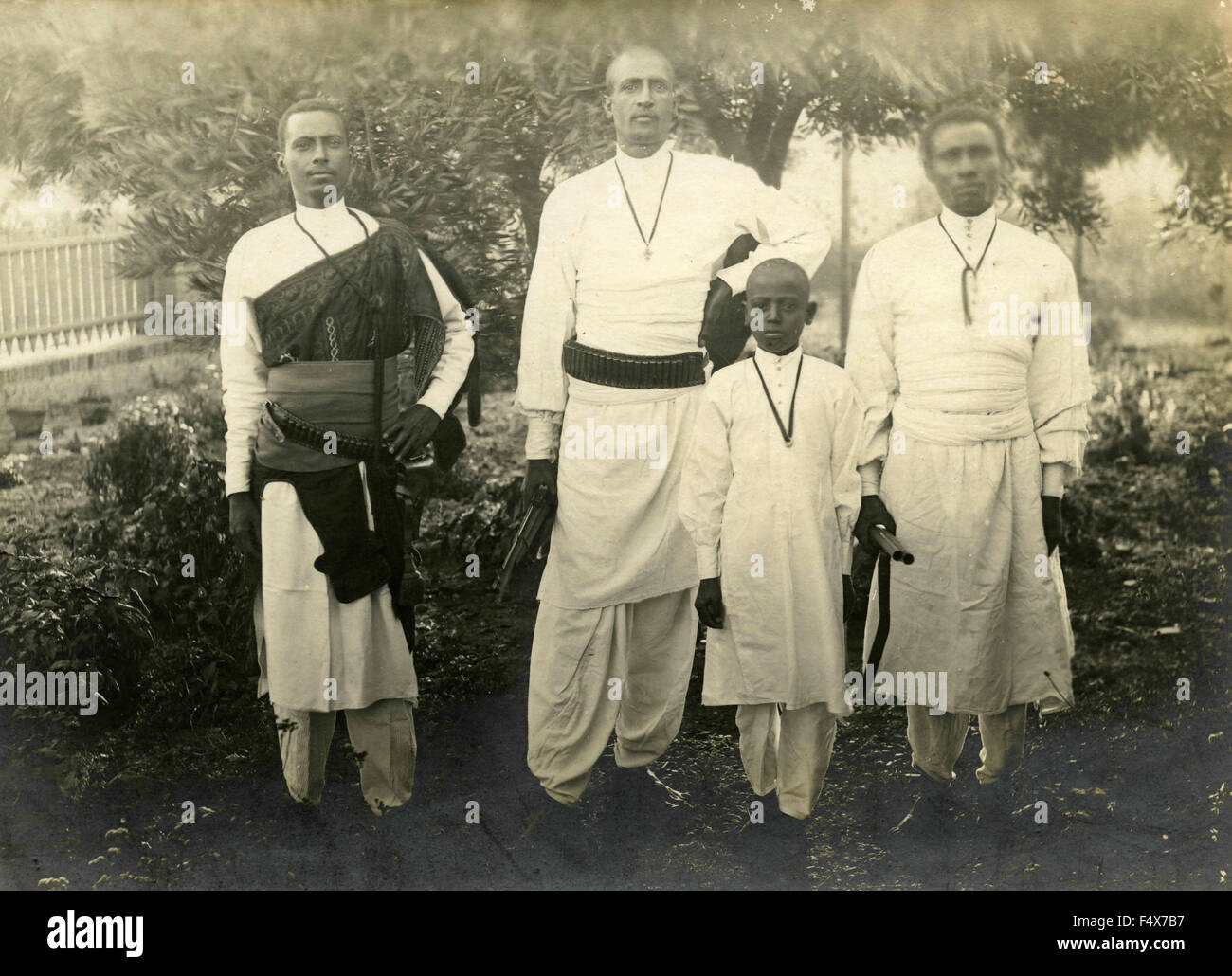 Three men and a child dressed in white with guns and ammunition, India ...