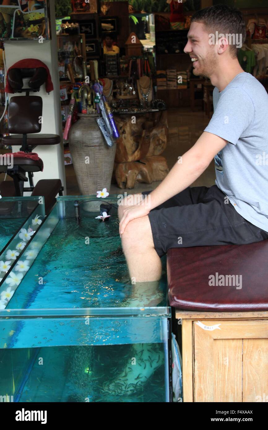 BALI, INDONESIA - JULY 6 2012: Boy doing feet pedicure with fishes in ...