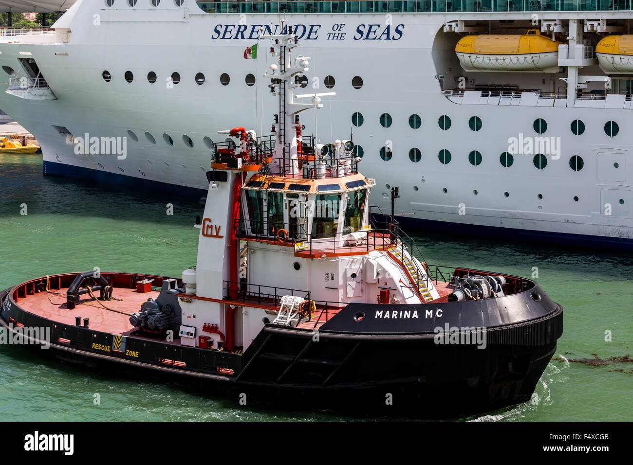 A large tugboat by a white luxury cruise ship Stock Photo - Alamy