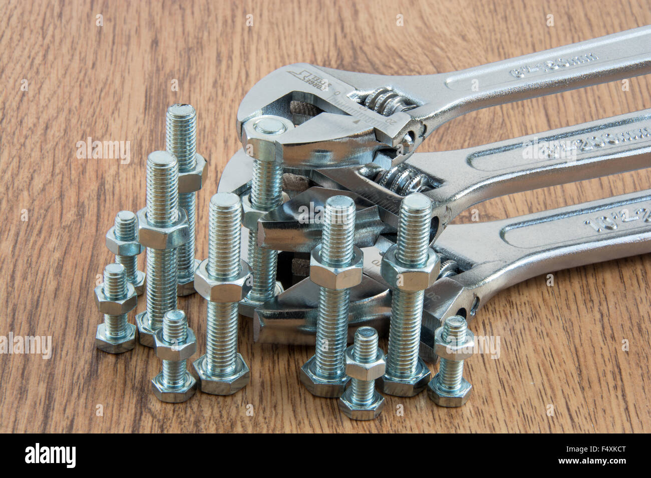 Stack of three adjustable wrenches with upright nuts and bolts in front ...