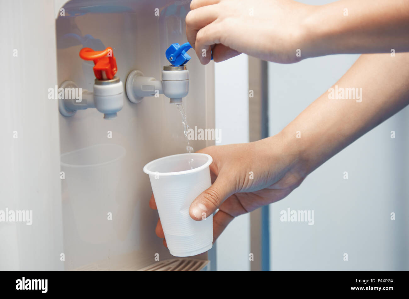 Man filling plastic cup at water cooler Stock Photo - Alamy