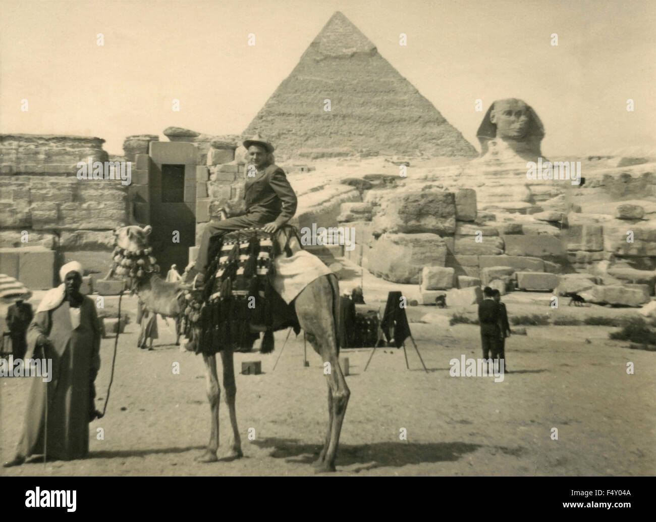 A man on a camel with the sphinx and a pyramid in the background, Egypt ...