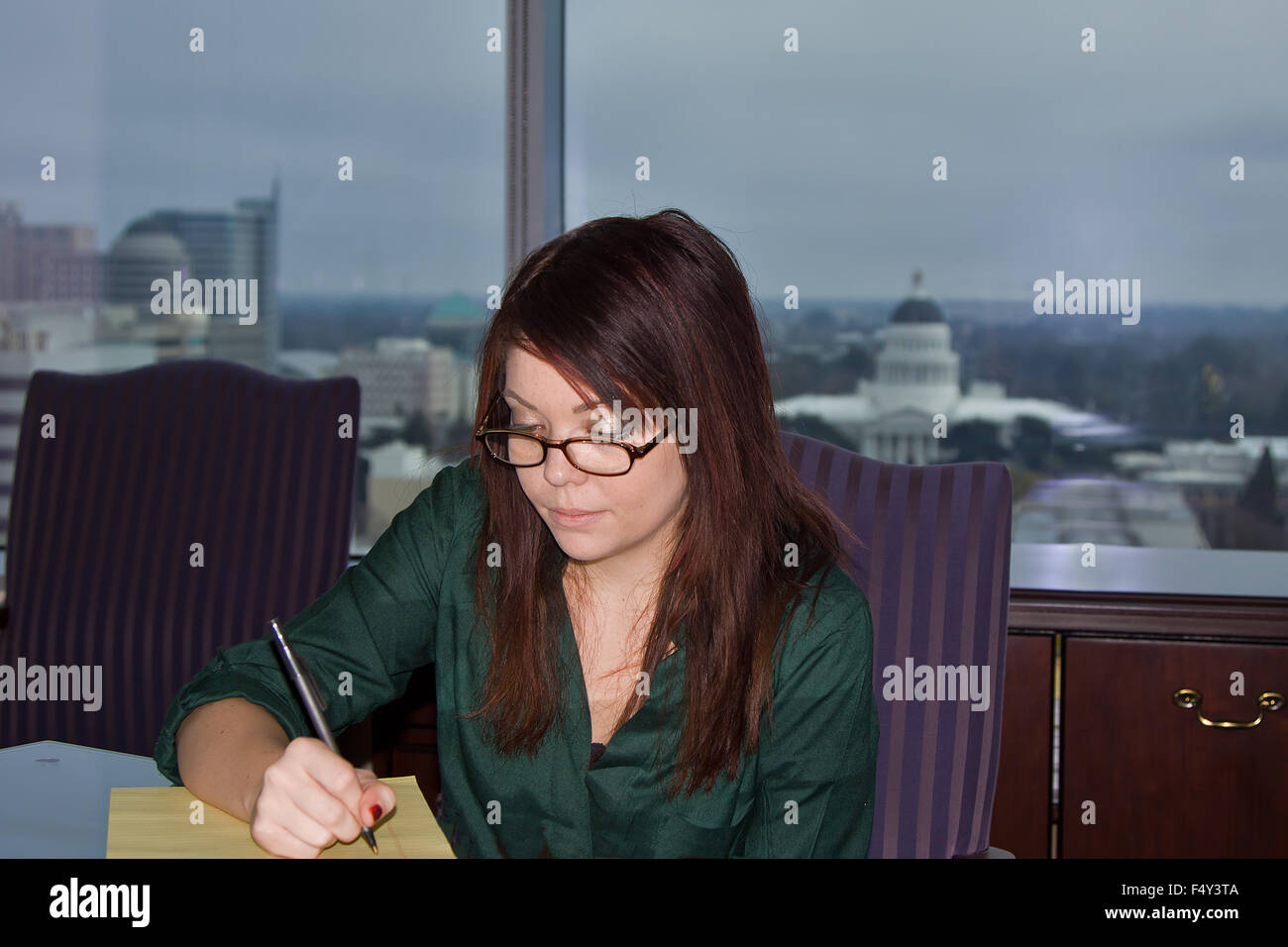 A young executive woman at her desk with a view of the California State ...