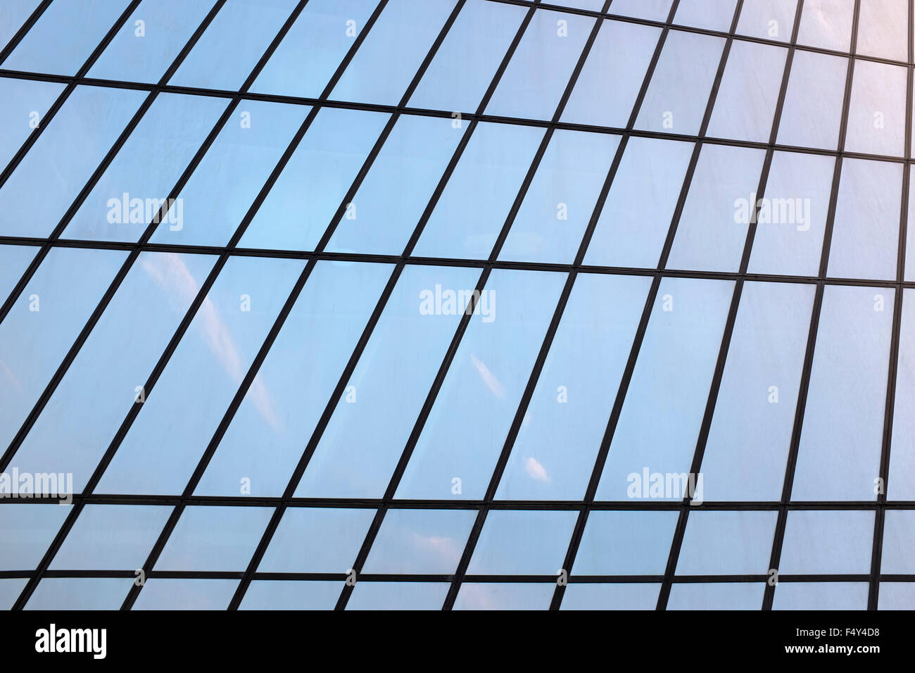 An office tower windows reflecting an early morning image of clouds and ...