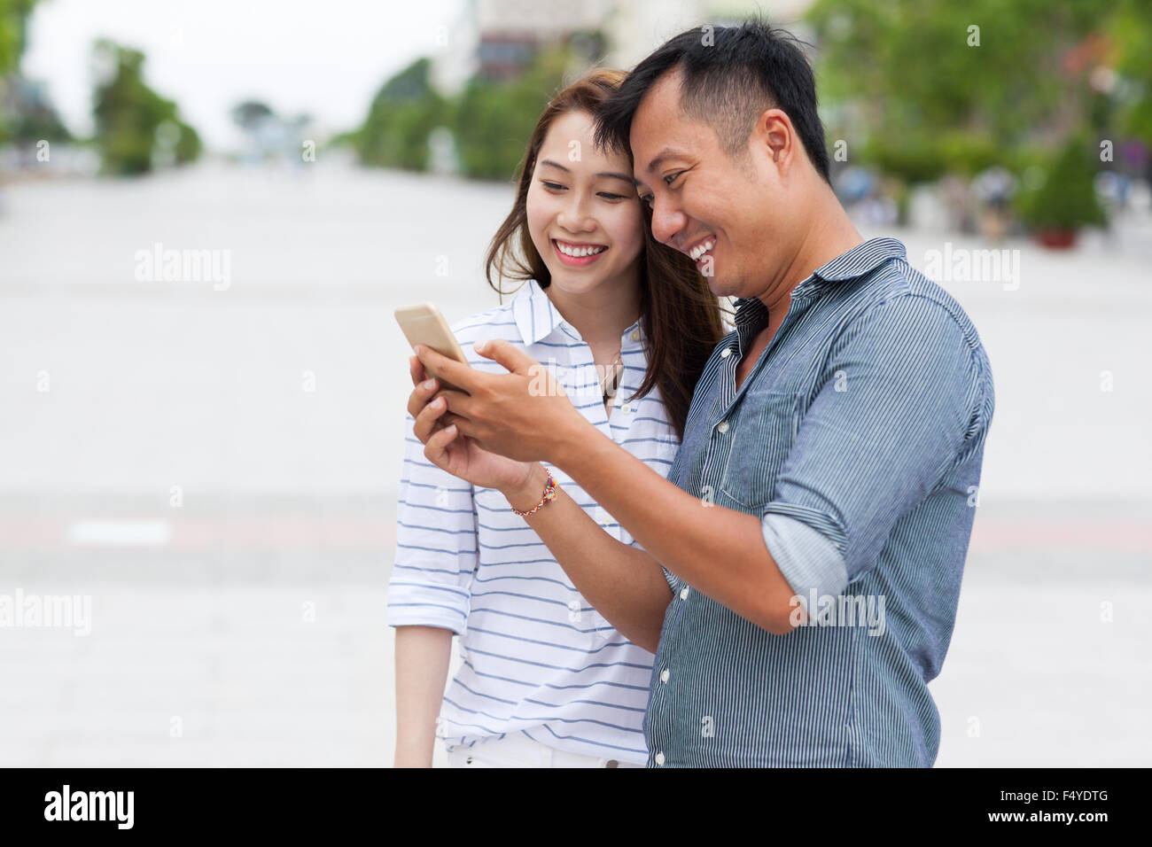 Asian couple using cell smart phone message smile Stock Photo - Alamy