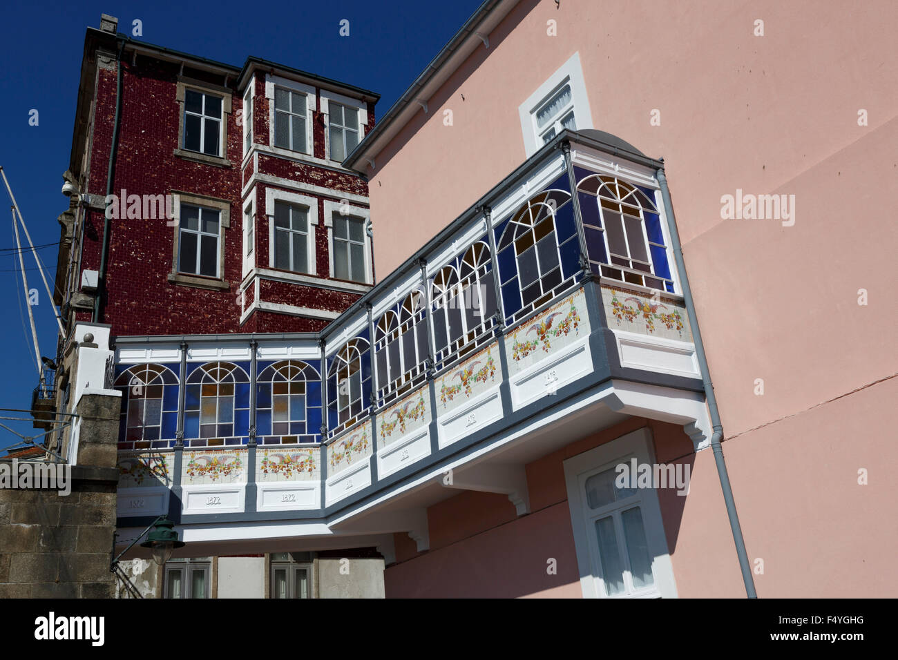 Ornate balcony with stained glass windows on a pink sided building ...