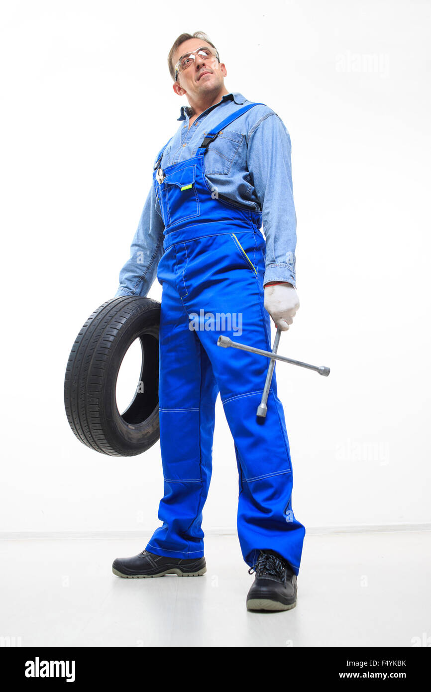 adult male mechanic with a wrench and tire Stock Photo - Alamy