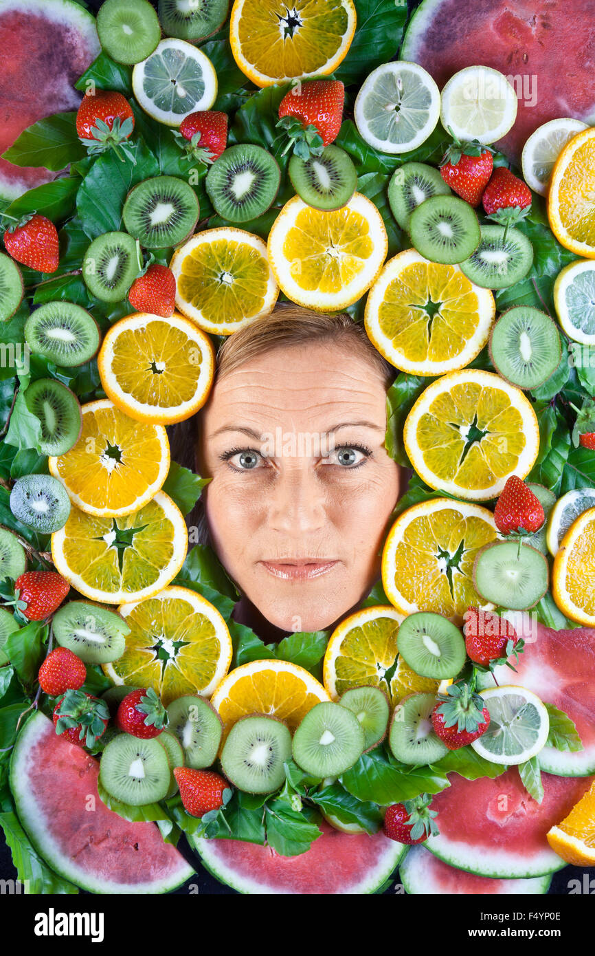 Many fruits stacked together around the head of a cute blond woman ...