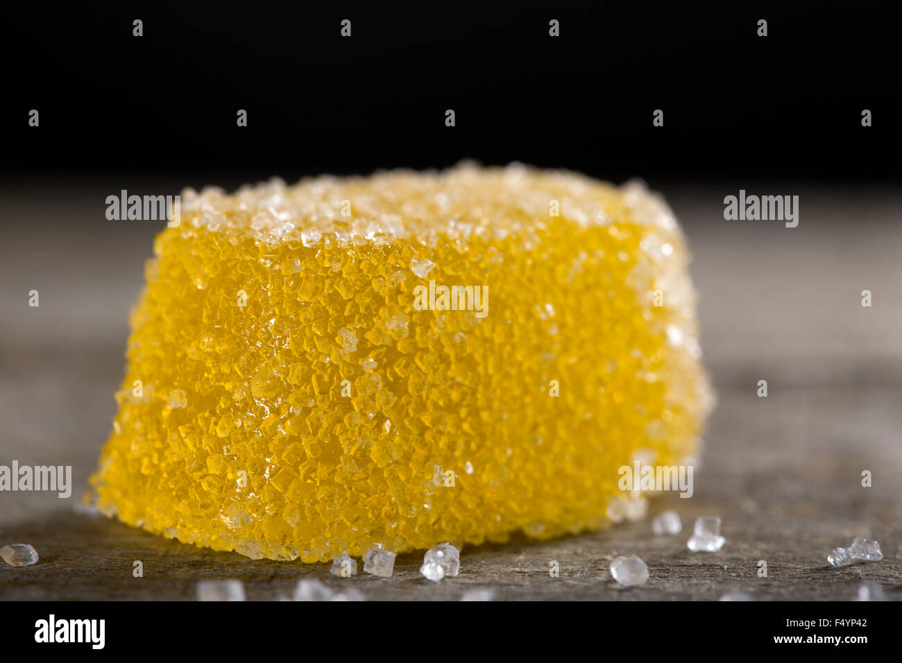 One yellow jelly candy with white sugar over wooden background Stock ...