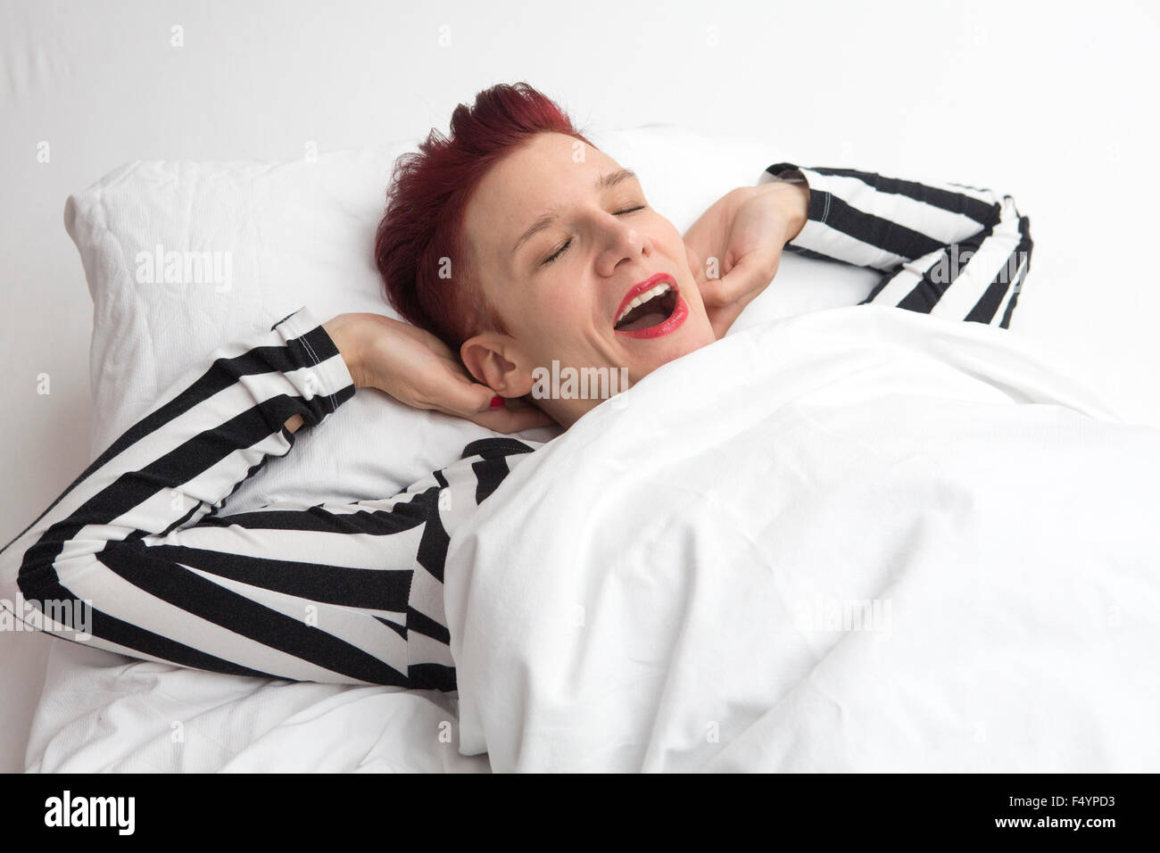 red-haired woman waking up in the morning and stretching and yawning ...