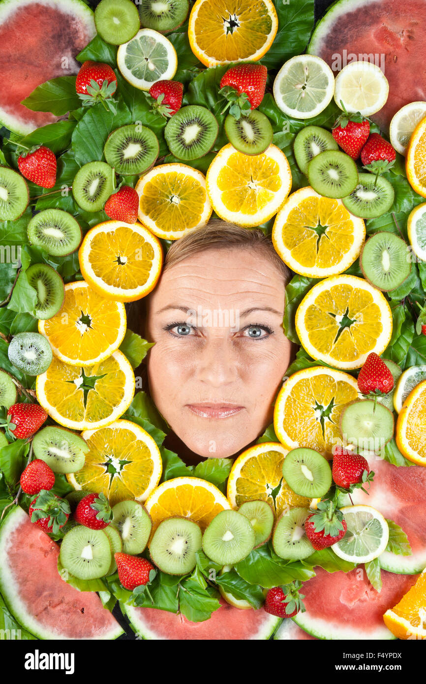 Many fruits stacked together around the head of a cute blond woman ...