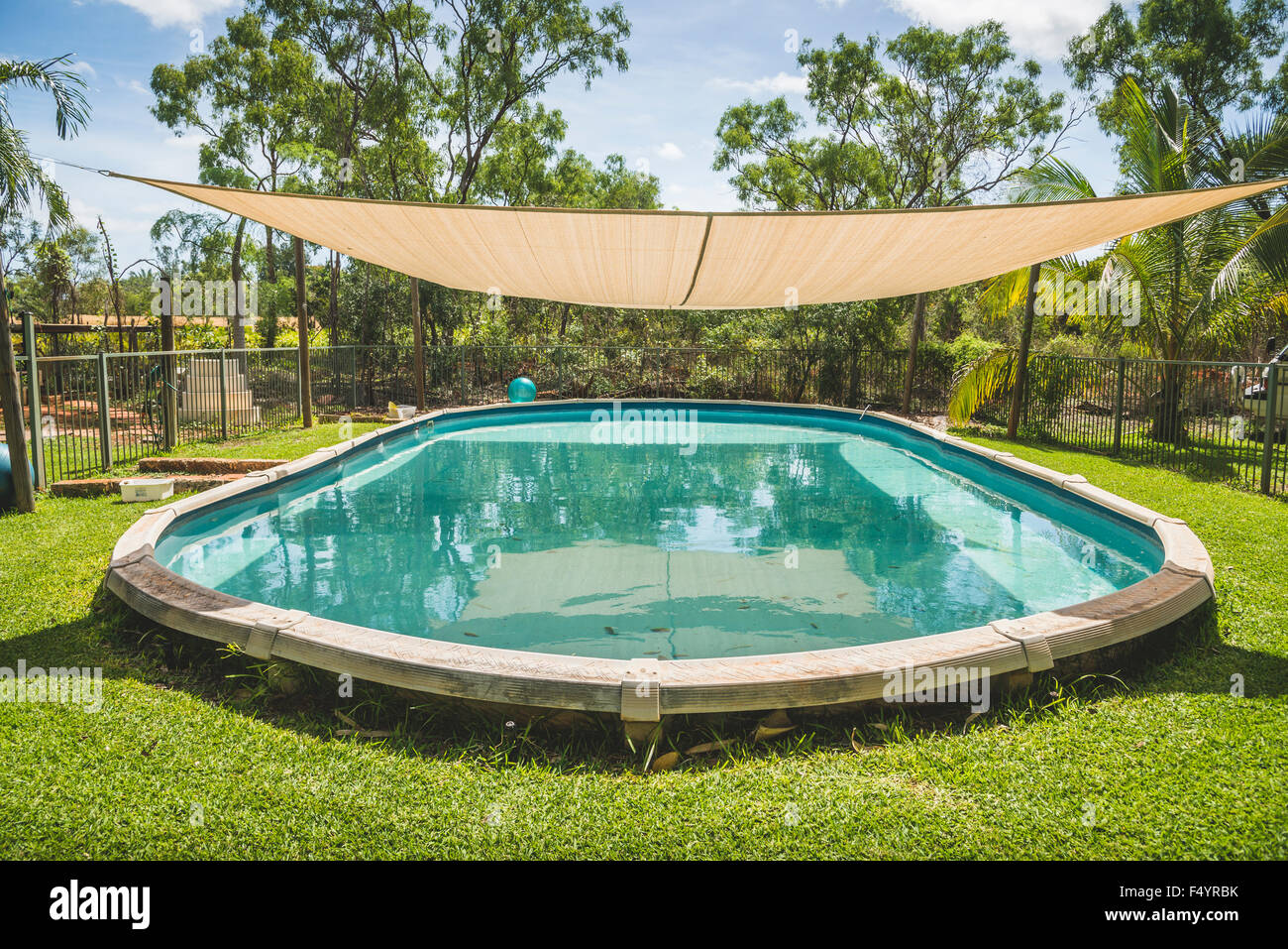 Swimming pool with tarp above, surrounded by grass and trees Stock ...