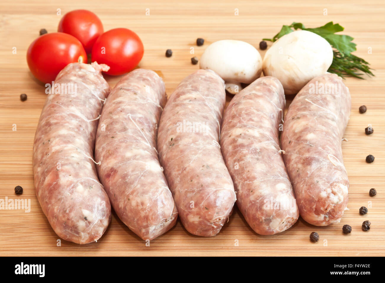 Uncooked sausage with vegetables on the chopping board Stock Photo - Alamy