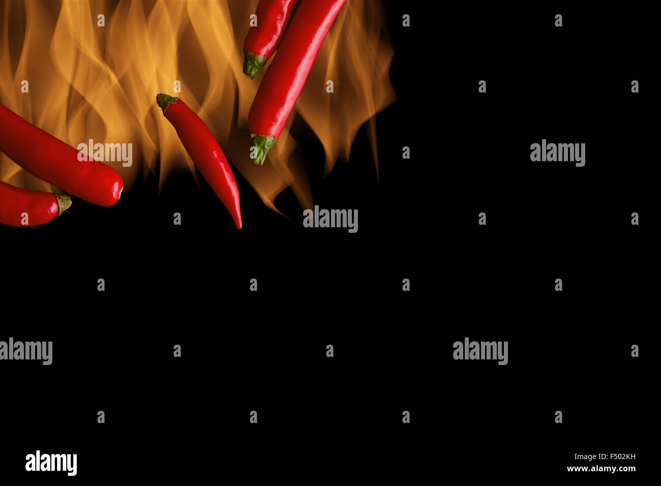Red chili pepper on flame or fire over black background Stock Photo - Alamy