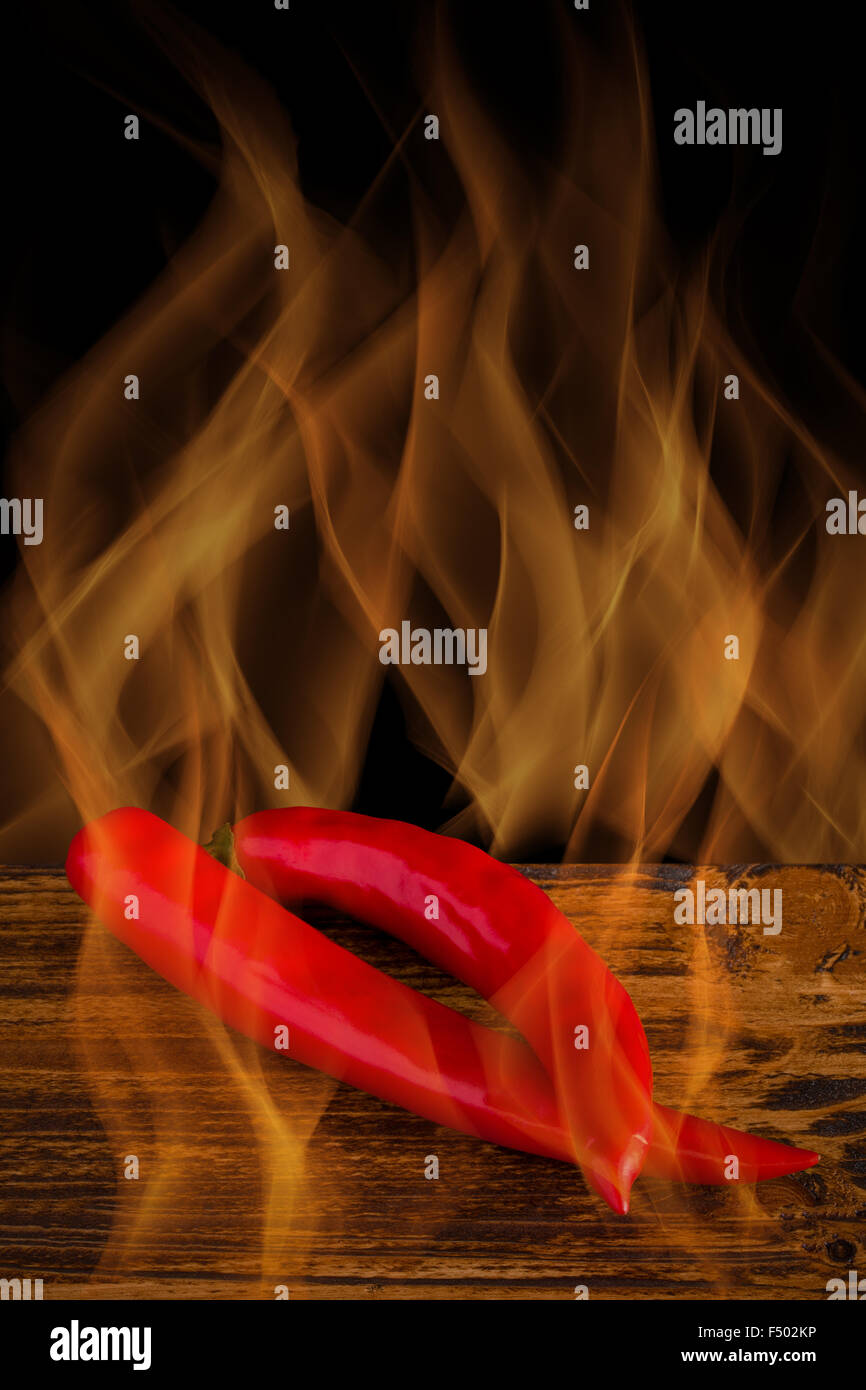 Red chili pepper on flame or fire over black background Stock Photo - Alamy