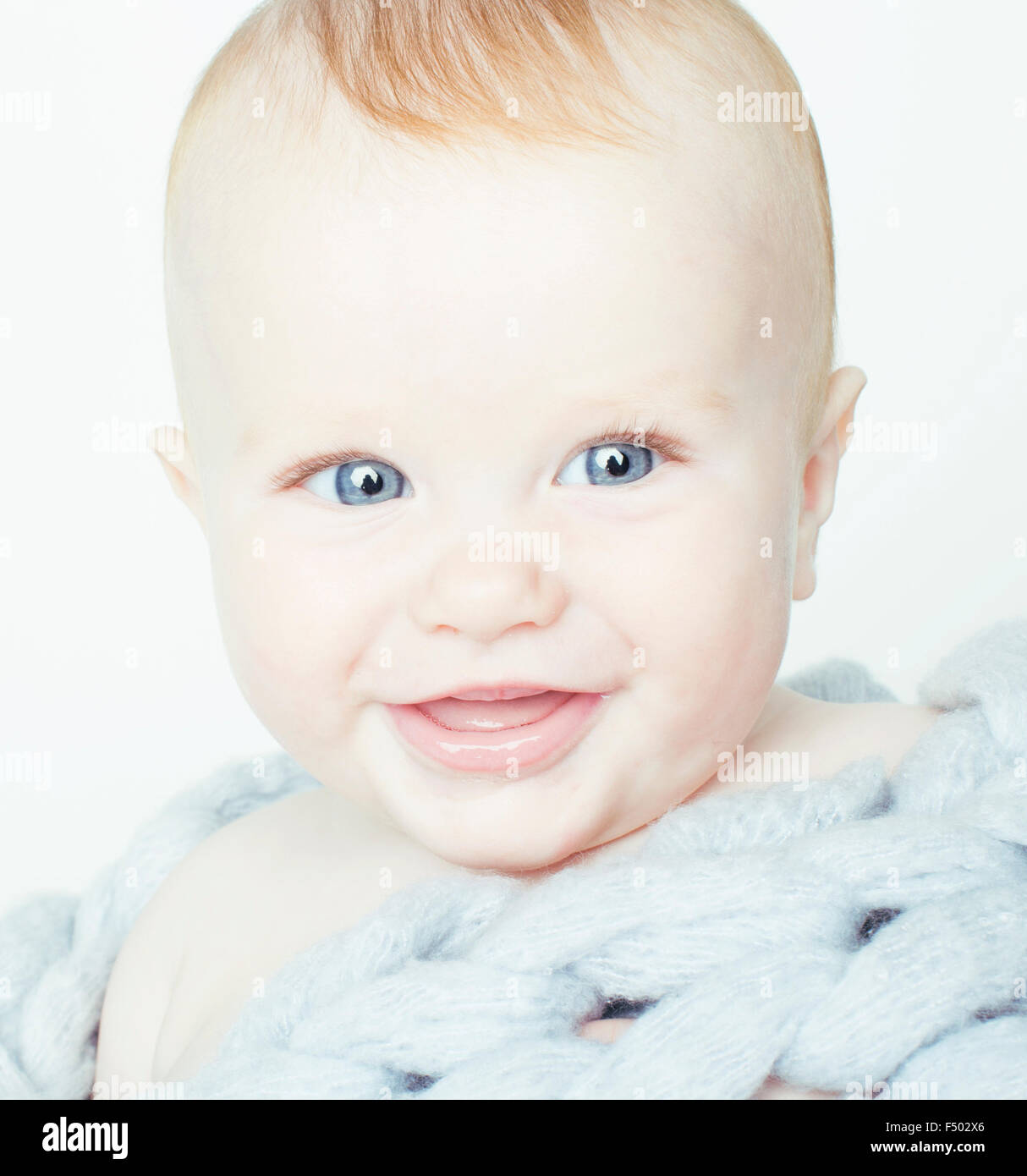 little cute red head baby in scarf all over him close up isolated ...