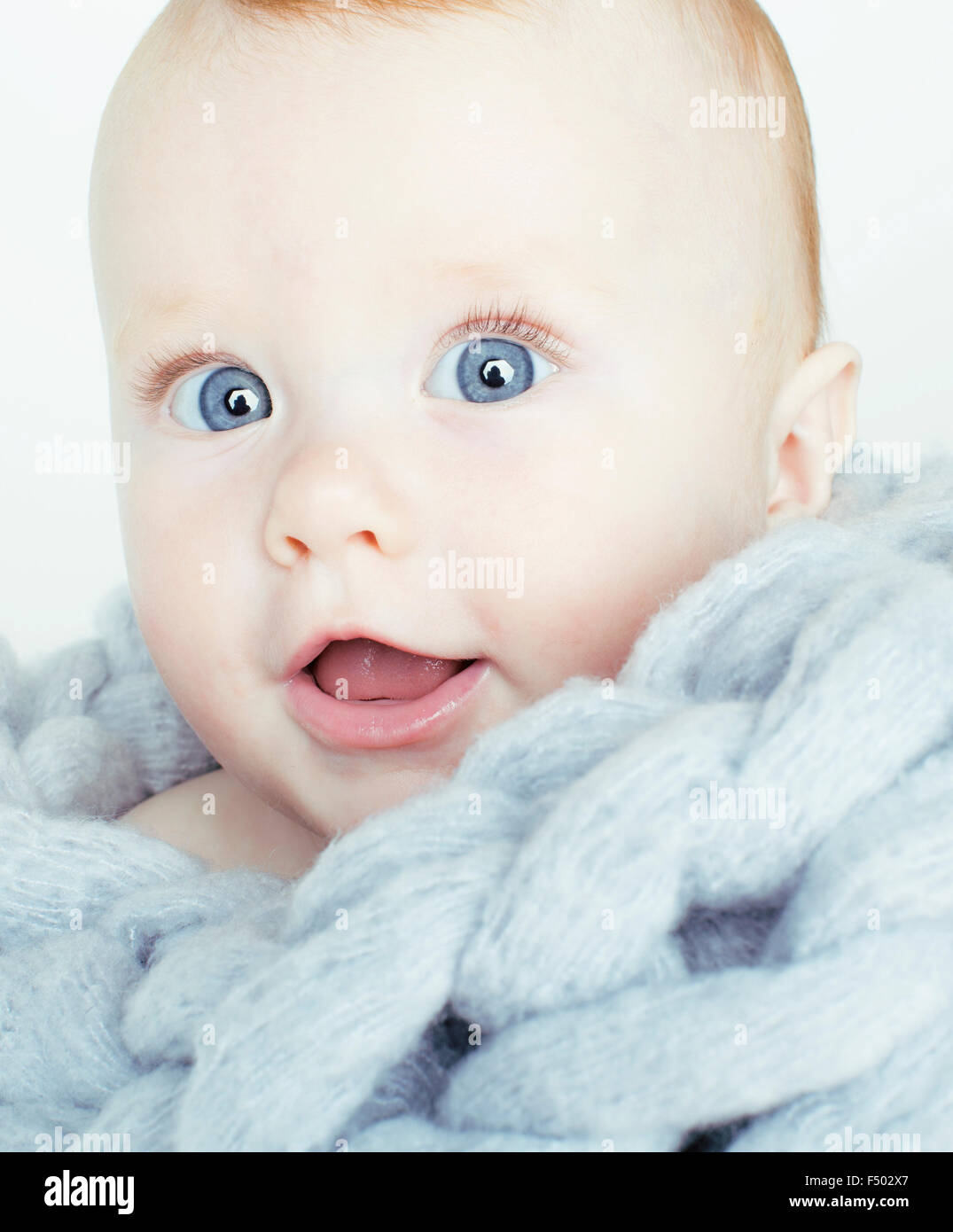 little cute red head baby in scarf all over him close up isolated ...