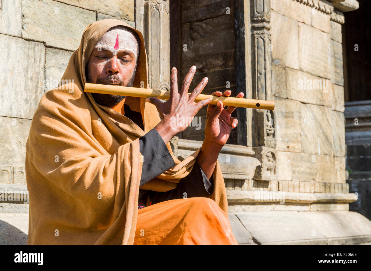 Young man playing flute at the burning ghats near Pashupatinath Temple ...