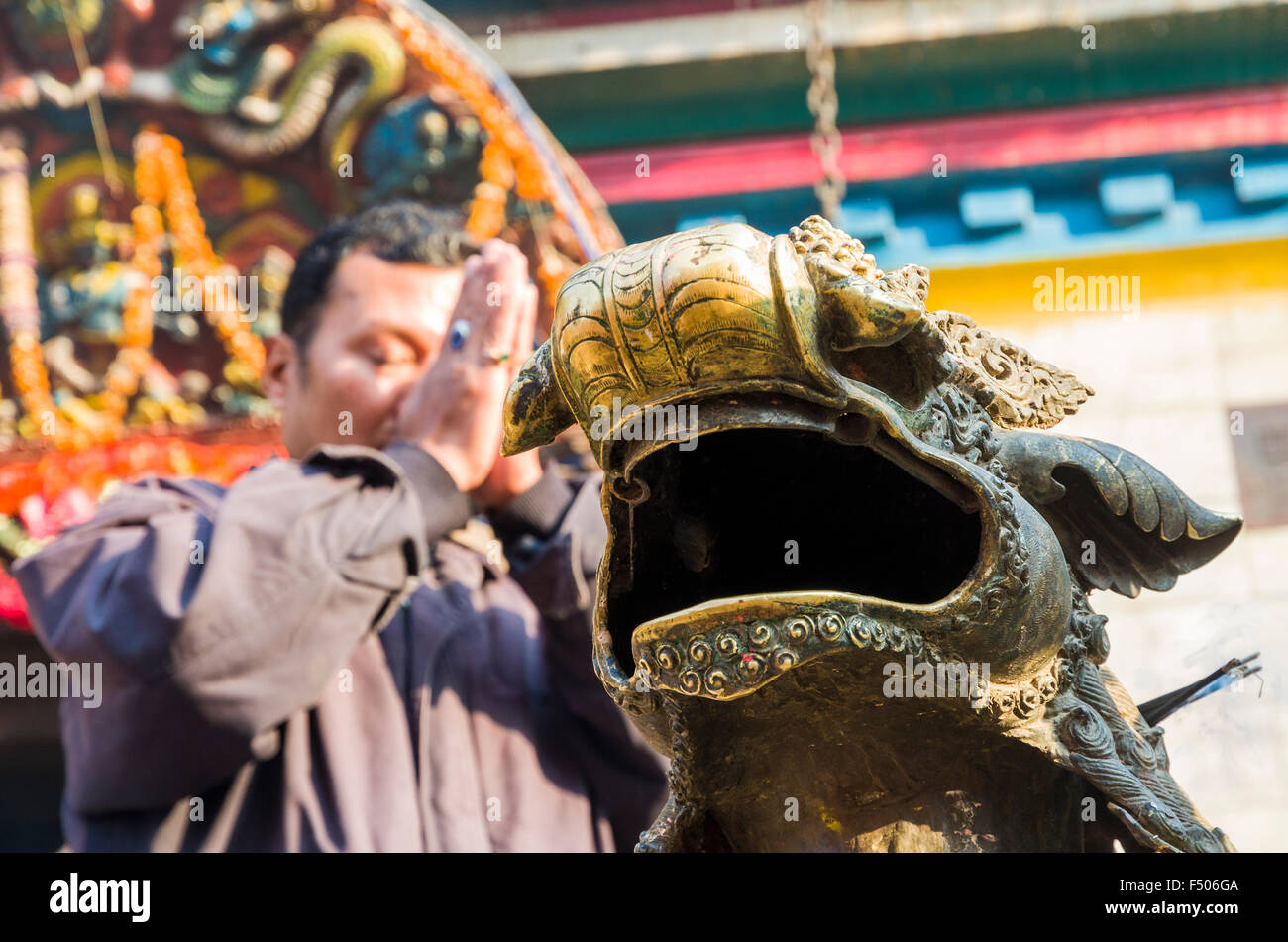 Head of a brass statue of a deiti, praying man in the background Stock ...