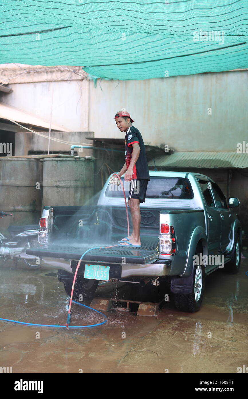 Man standing on loading area cleaning pickup truck with a hose. crisp ...
