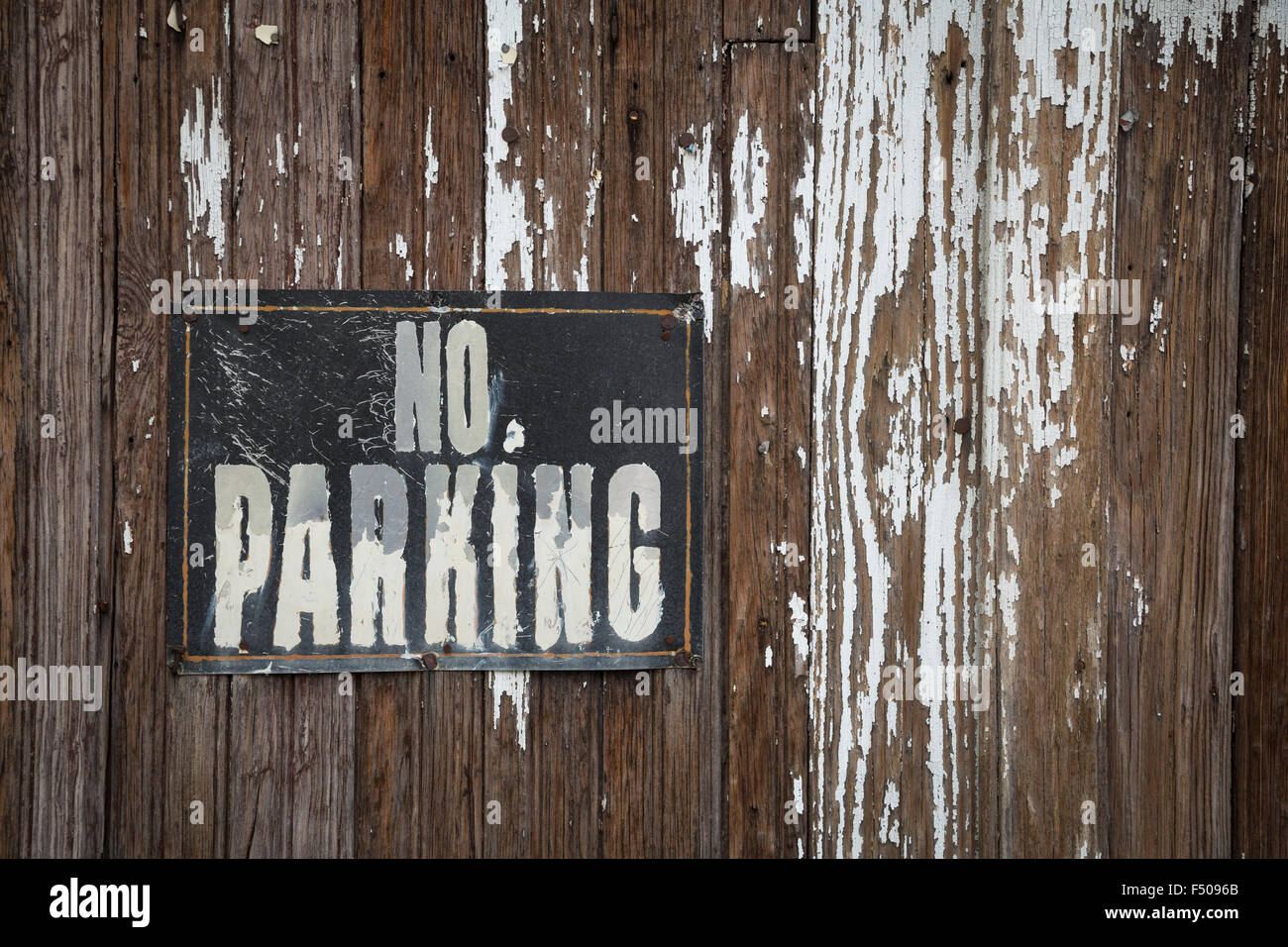 No parking sign on the side of a weathered, wooden fence Stock Photo ...