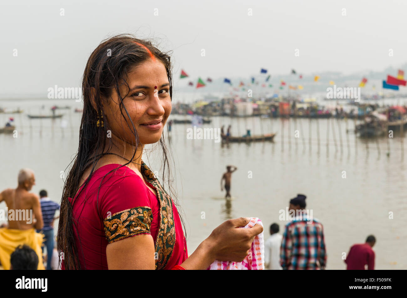 Young woman in red sari smiling at the Sangam, the confluence of the ...