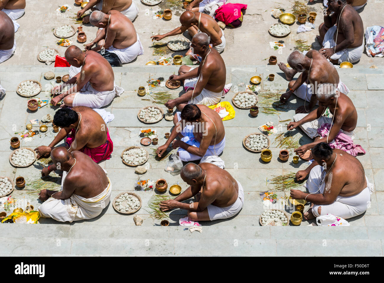 A group of male pilgrims is performing a pooja, a religious ceremony ...