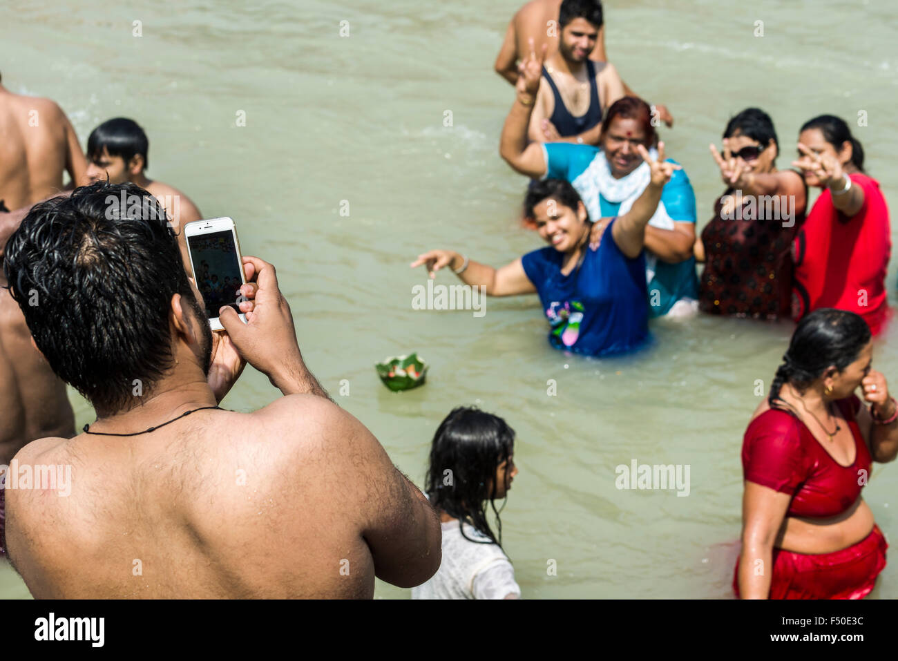 A man is taking a photograph of his family bathing at Harki Pauri Ghat ...