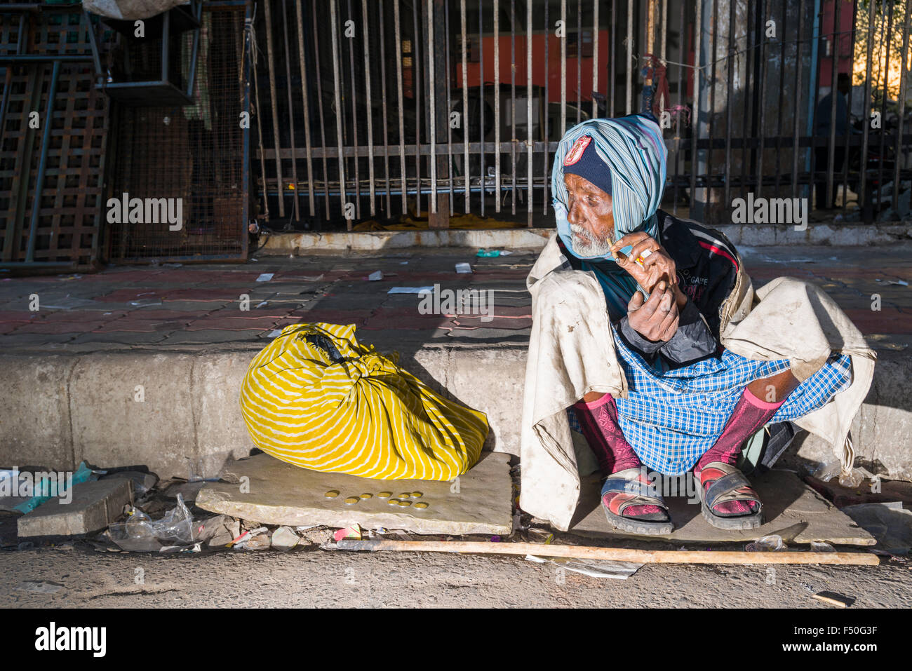 A homeless beggar is sitting on the pavement after spending the night ...
