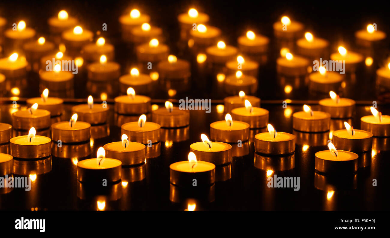 Panorama of the many burning candles with reflection in the mirror ...